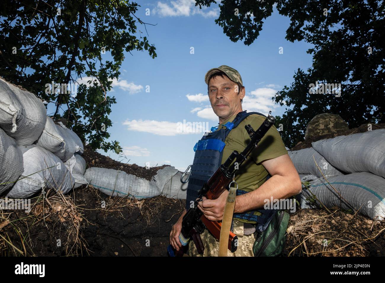 A Ukrainian soldier with a machine gun in a trench in a combat position ...
