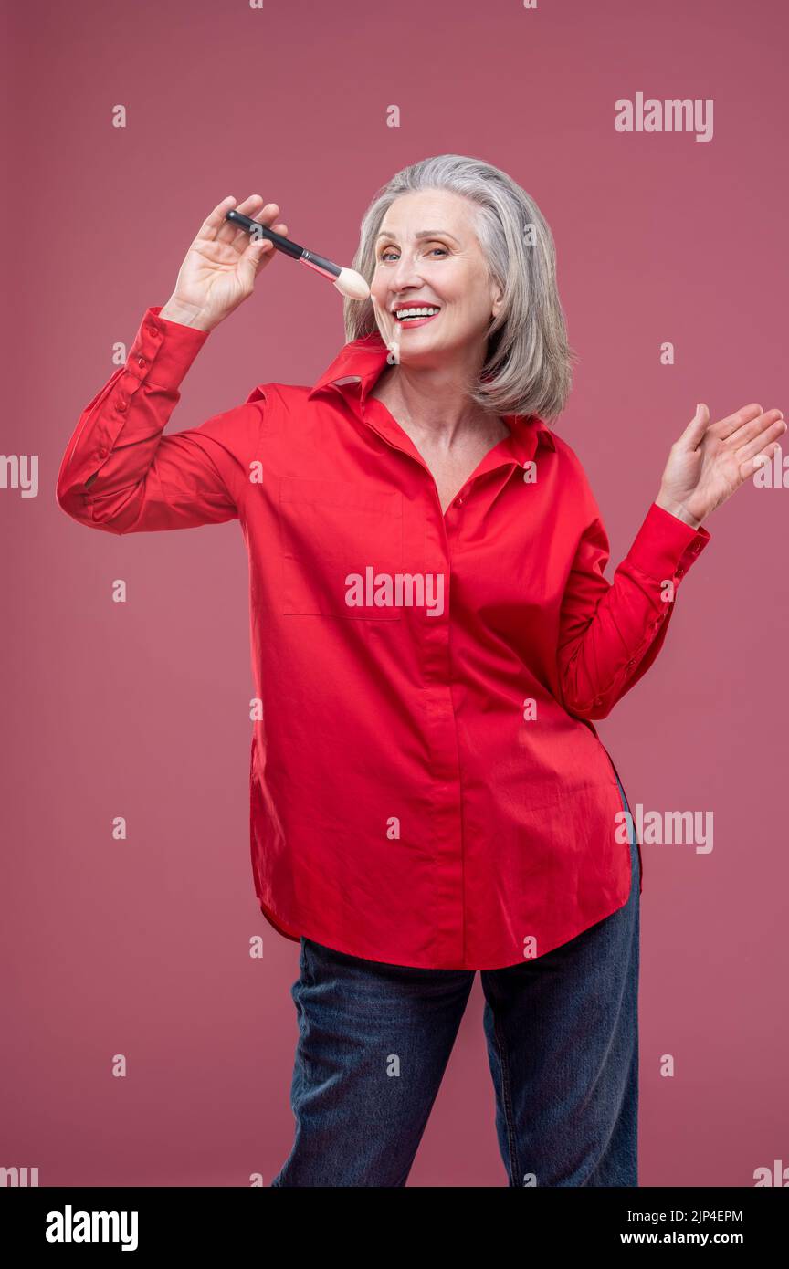 Smiling woman in red with a face brush in hand Stock Photo - Alamy