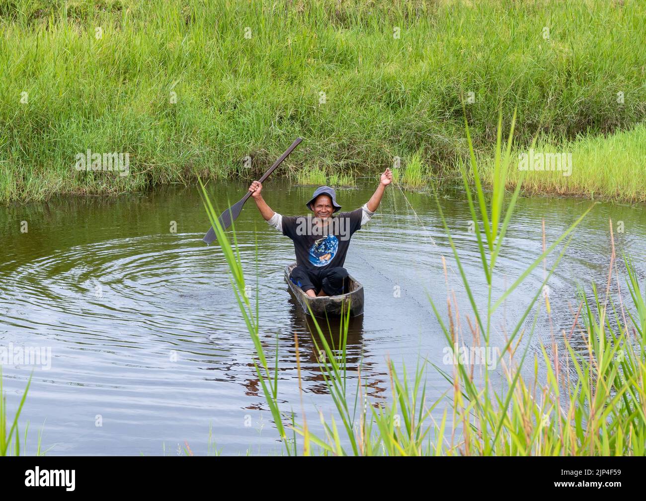 A local man in a dugout canoe fishing in a lake. Sulawesi, Indonesia ...