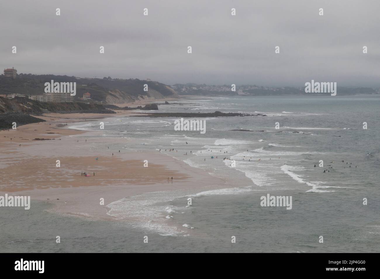A beautiful view of a beach and people in the water on a cloudy day in ...