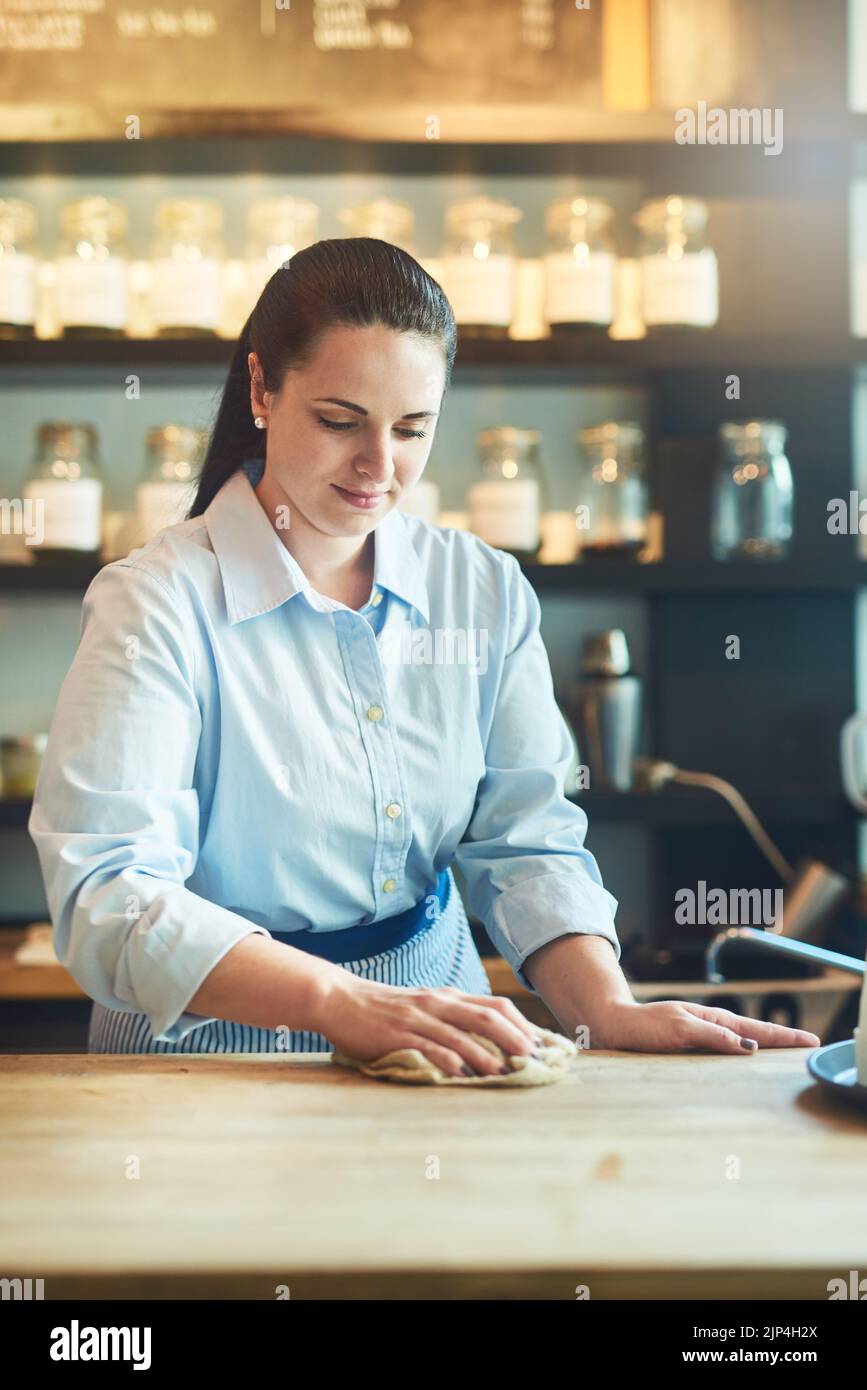 The cafe remains spotless under her management. a young woman cleaning ...