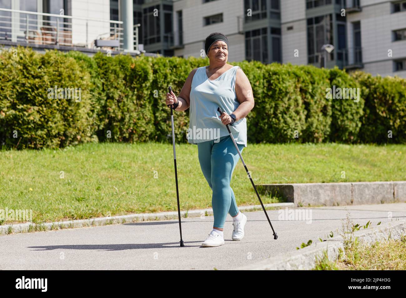 Full length portrait of smiling overweight woman walking outdoors with ...
