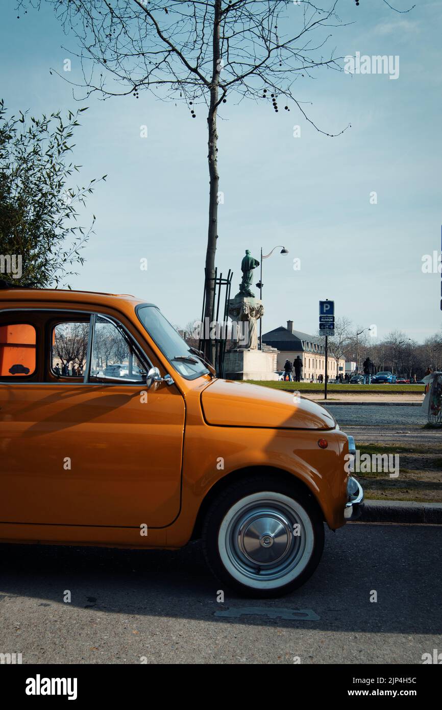 A vertical shot of a vintage Fiat 500 car in the streets of Paris ...