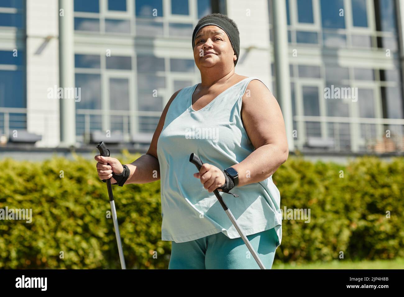 Low angle portrait of overweight woman walking outdoors with nordic ...