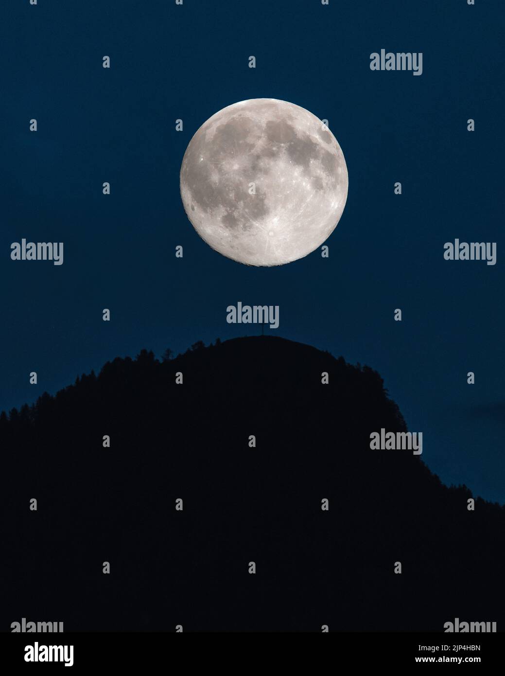 A vertical view of a beautiful full moon over a lovely hill during the ...
