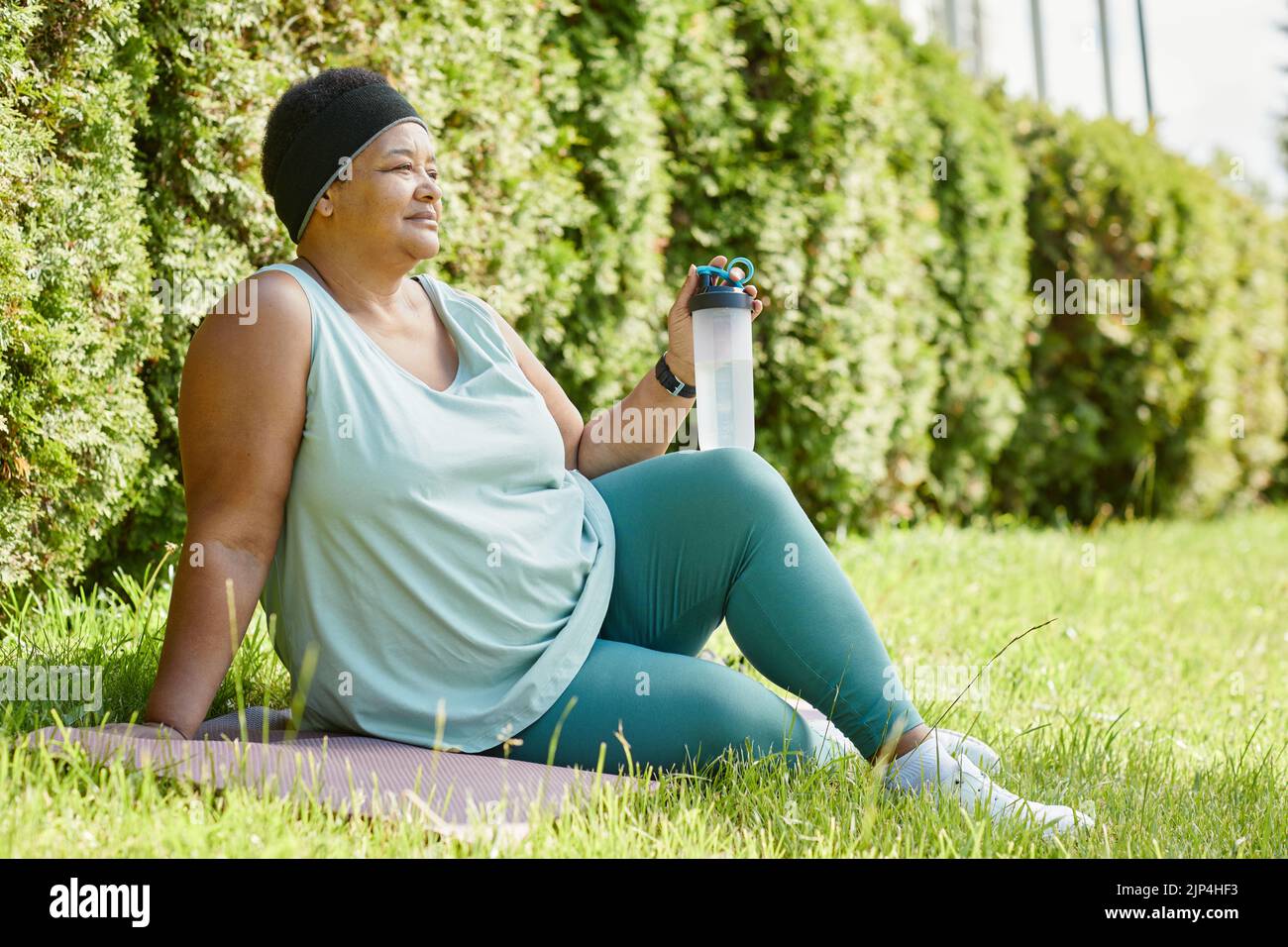 Full length side view of overweight black woman relaxing on grass while ...