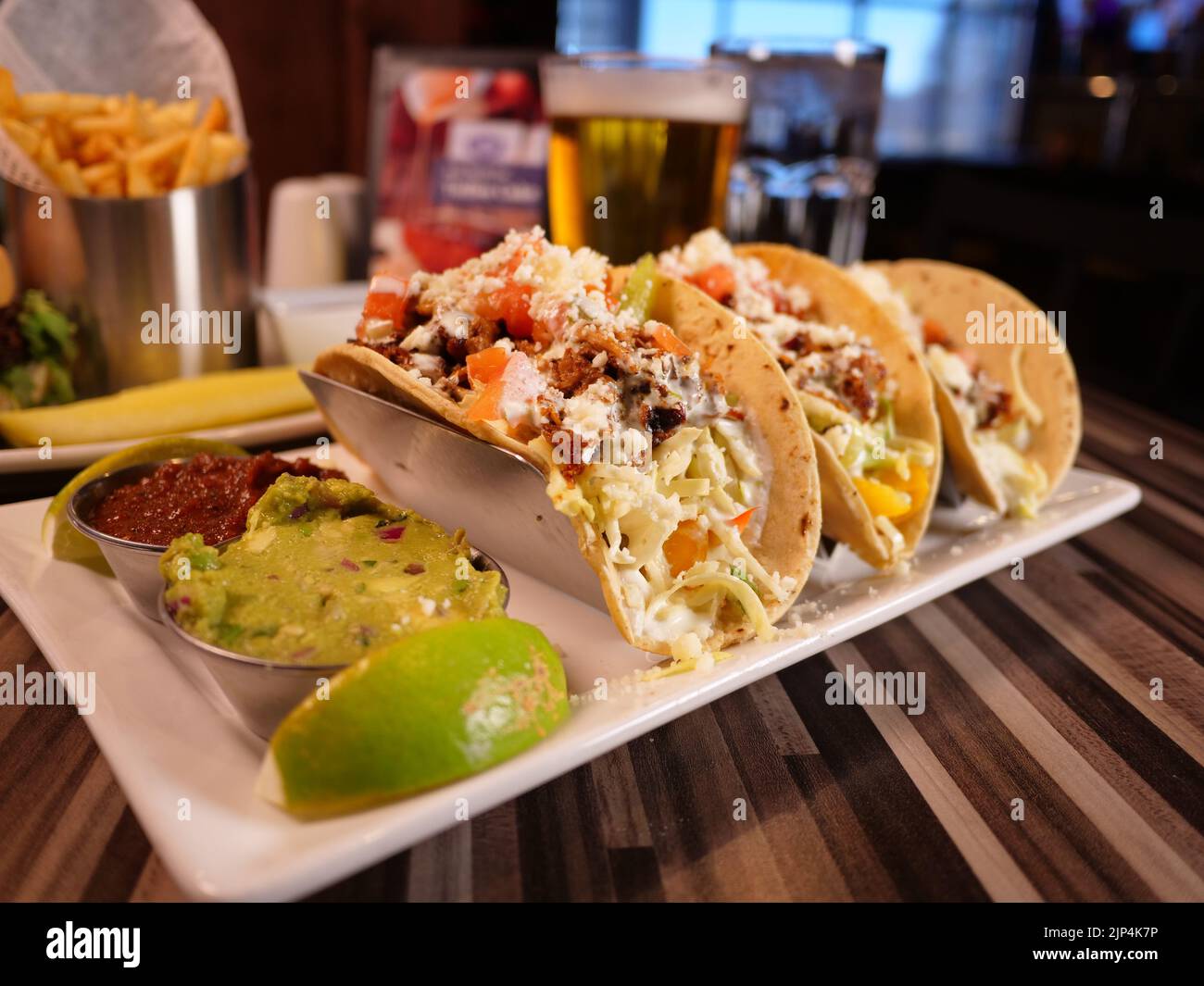 three Mexican tacos with sauce and lime Stock Photo - Alamy