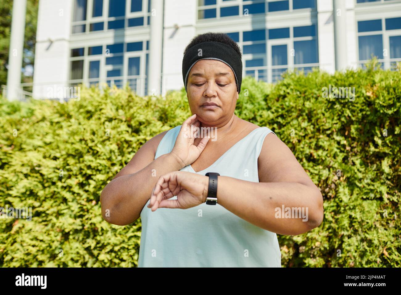 Waist up portrait of mature black woman looking at smartwatch and ...