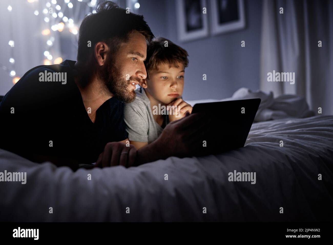 Learning late into the night. a father and his little son using a ...
