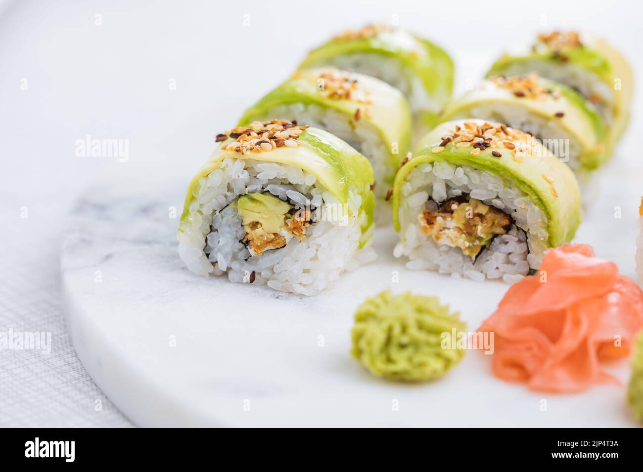 Sushi rolls on platter, bright background. Served with wasabi and ...