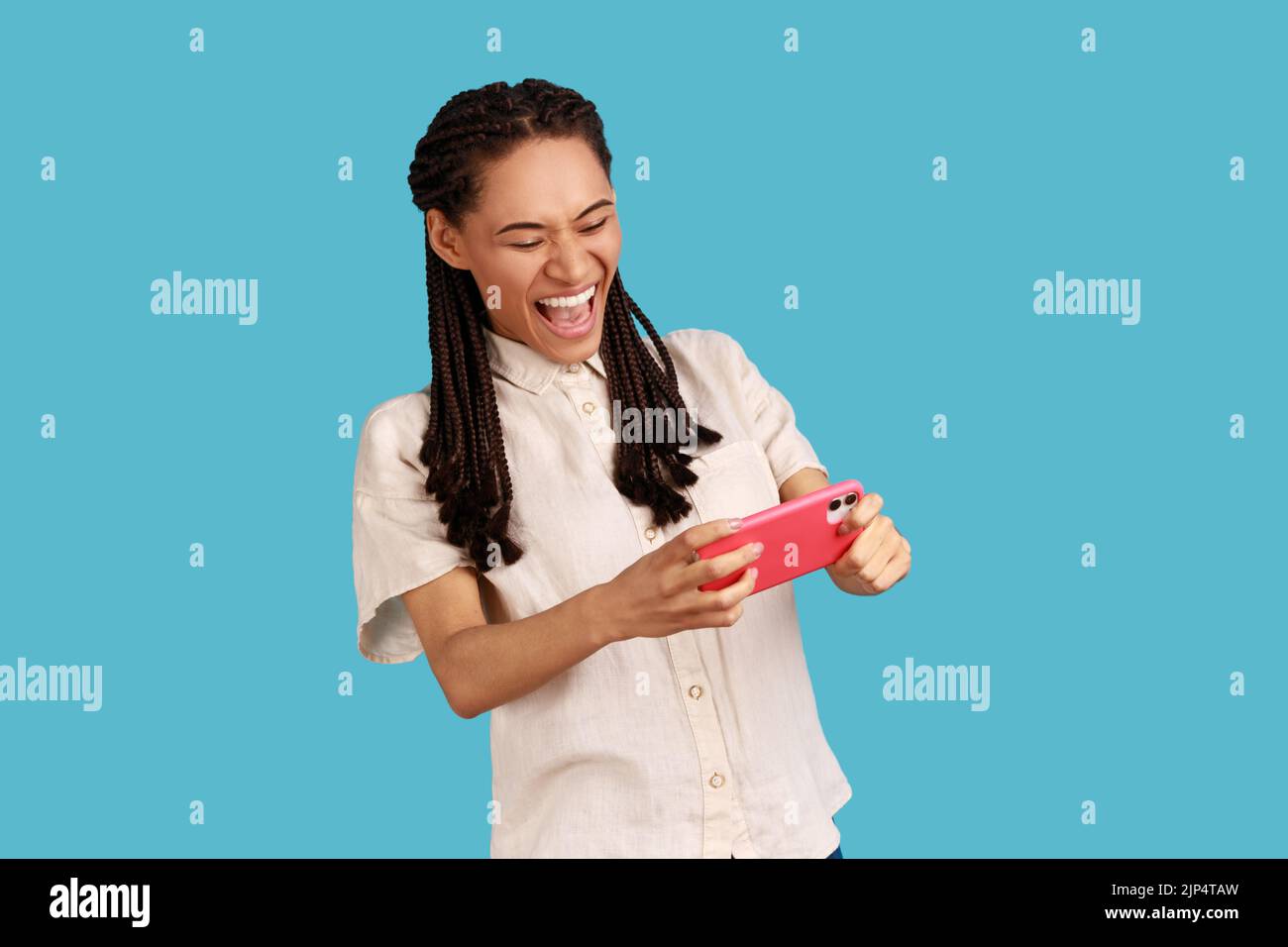 Emotional happy woman with black dreadlocks stares at smartphone camera ...