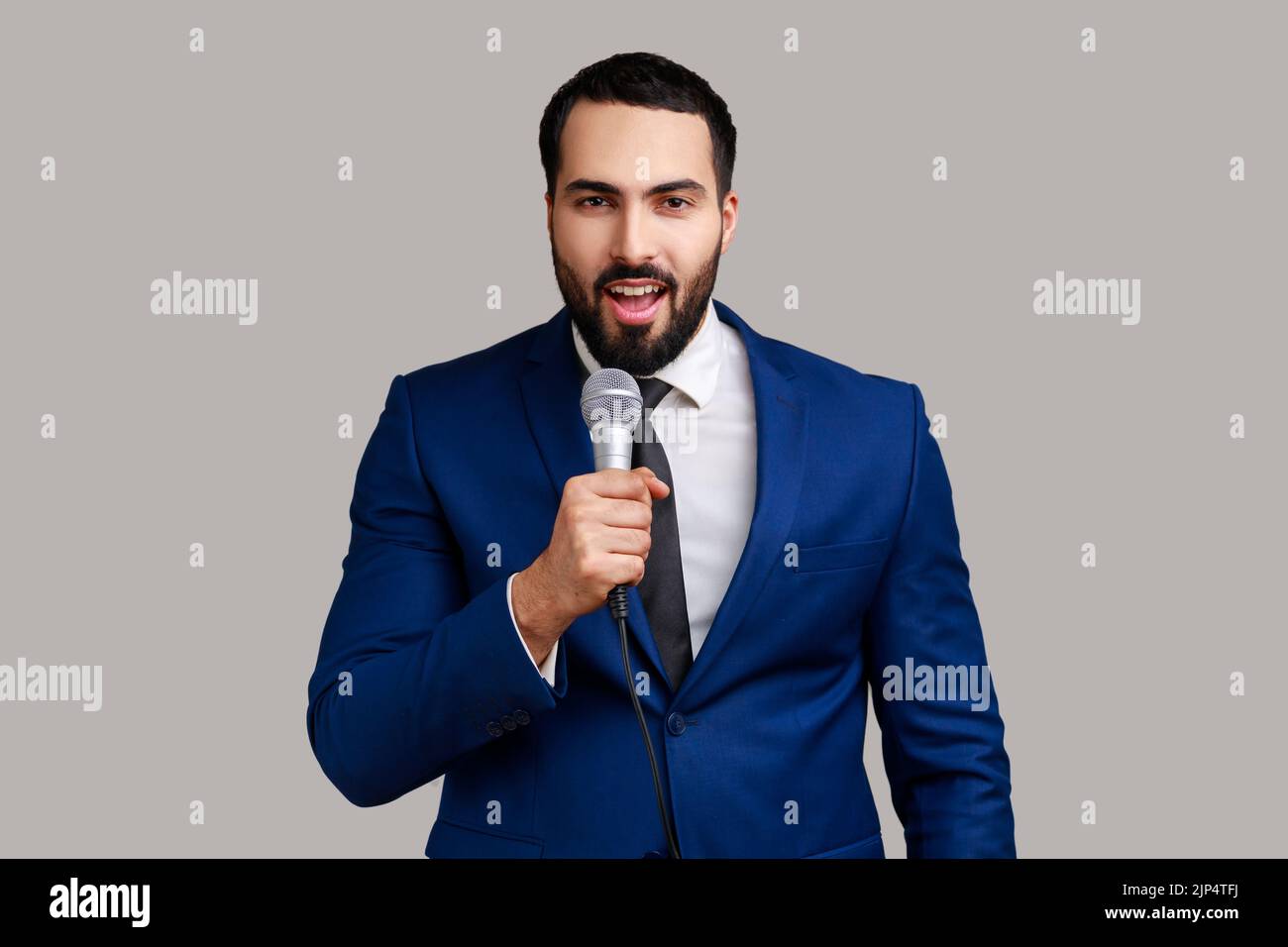 Positive handsome bearded man standing with microphone in hands, sing ...