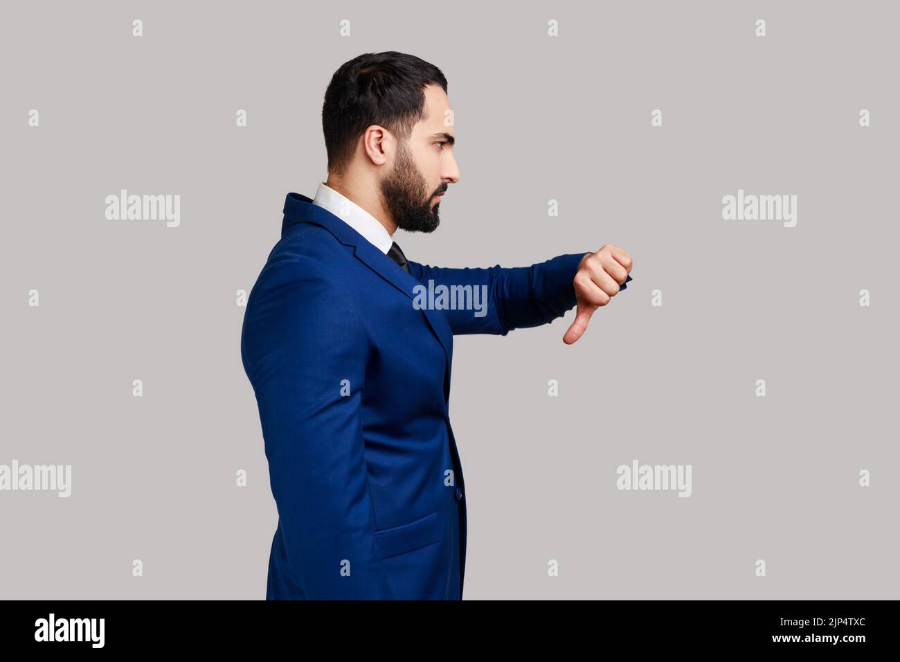 Side view of bearded man criticizing bad quality with thumbs down ...