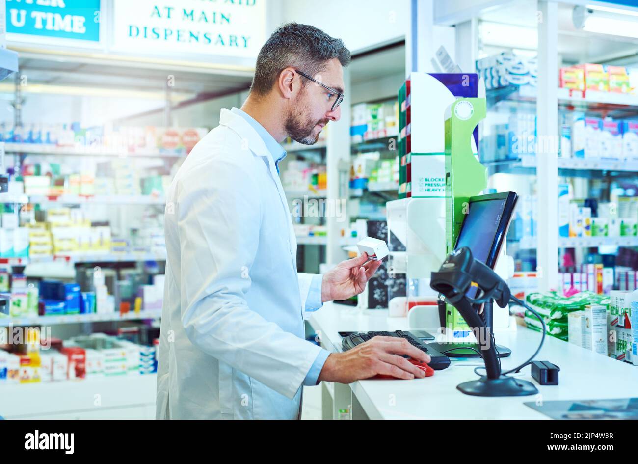Logging the medication. a handsome mature male pharmacist working in a ...