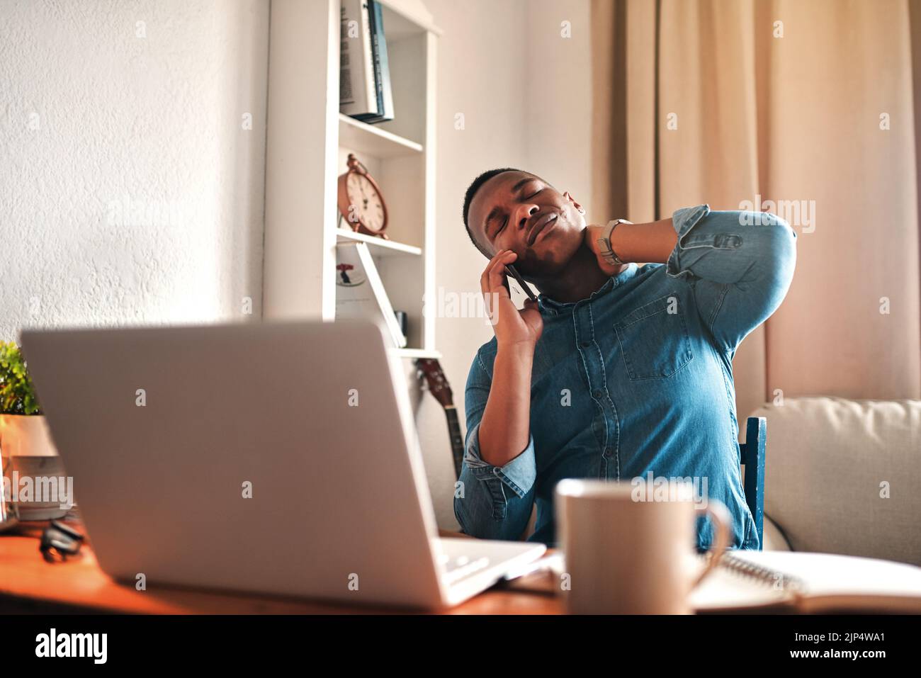 Tired business man with neck pain on a laptop and phone call, looking ...