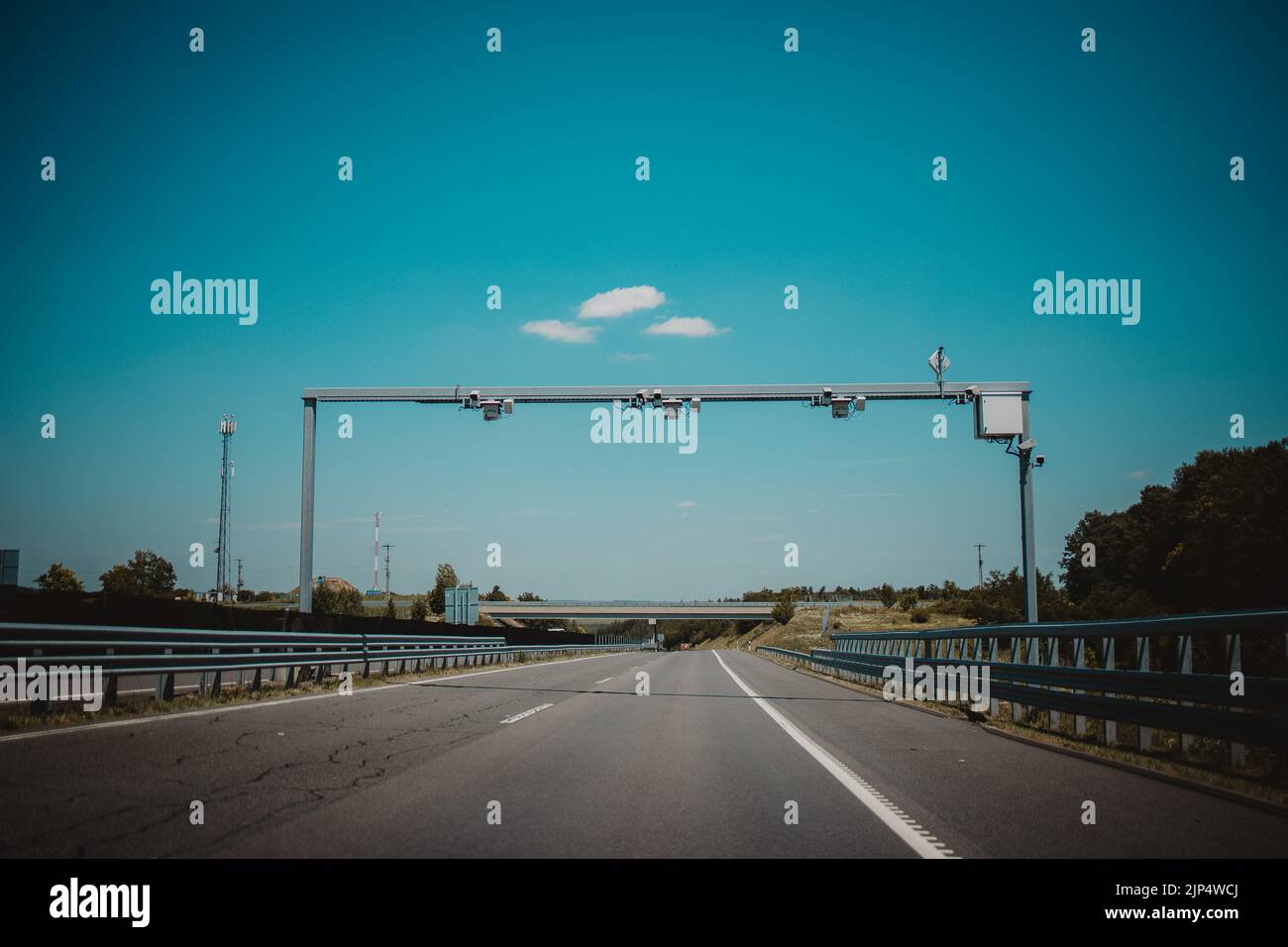 A clear highway road with white markings, railings and green trees ...
