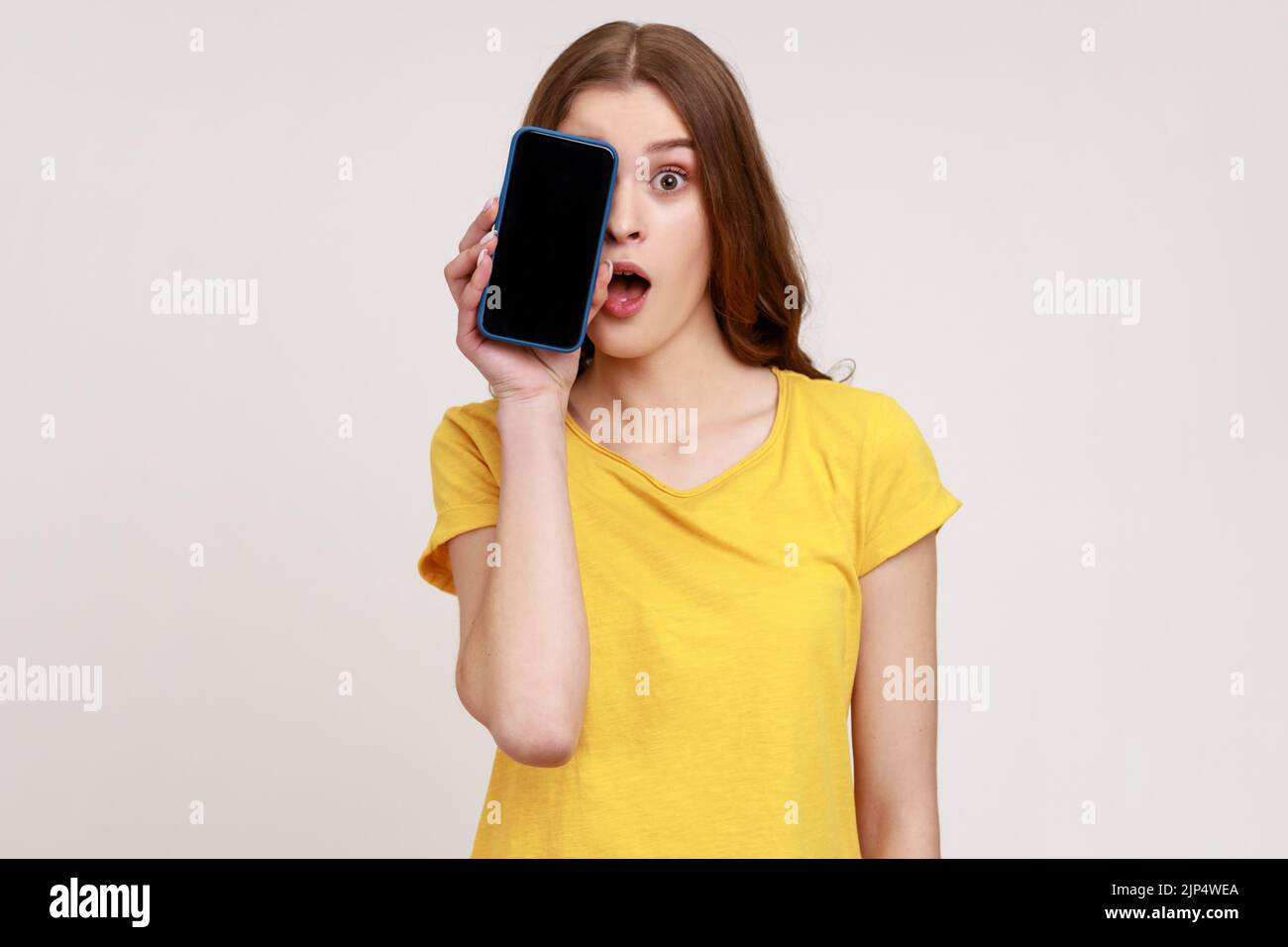Portrait of excited shocked teenager girl wearing yellow T-shirt ...