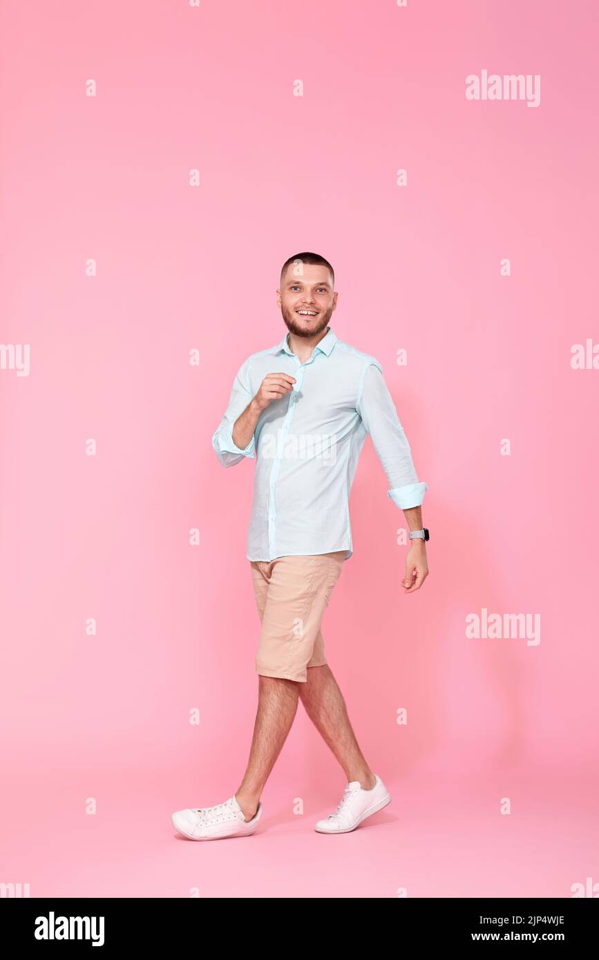 handsome man walks isolated on pink background Stock Photo - Alamy