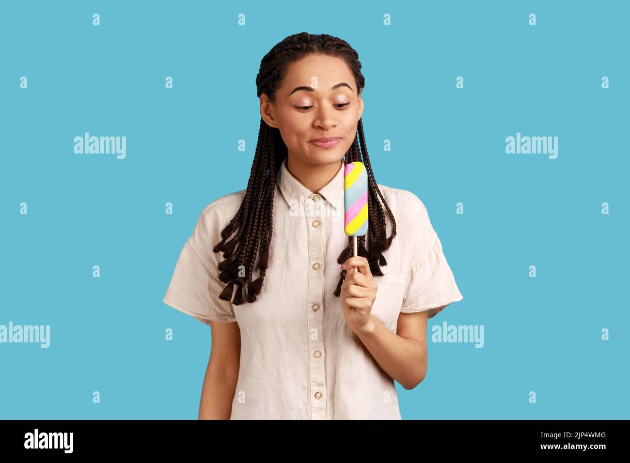Optimistic woman with black dreadlocks holding sweet colorful ice cream ...