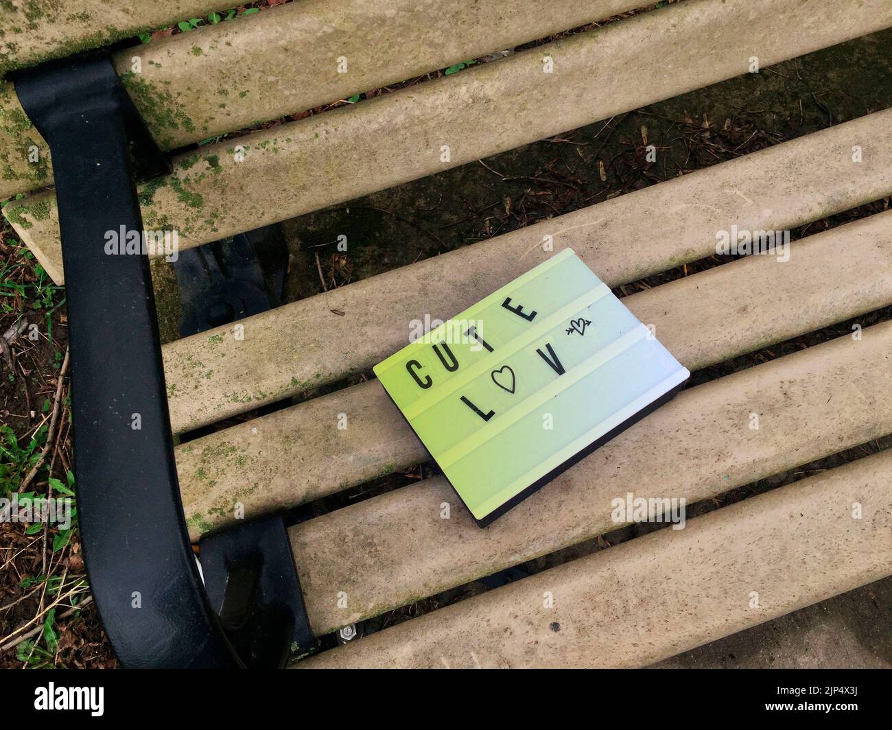 A message of love in letters and symbols on a light box. A park bench ...