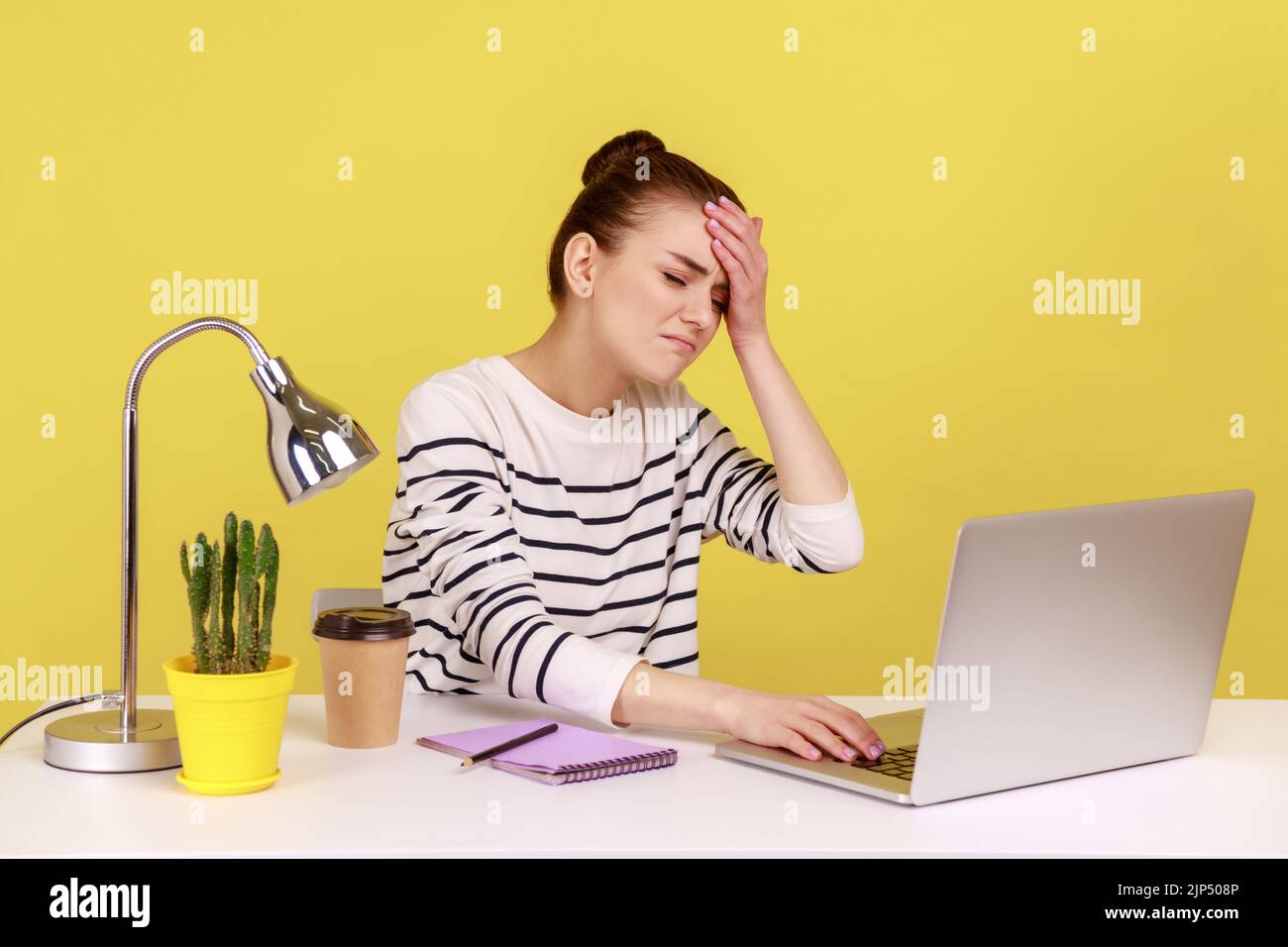 Forgetful woman manager sitting at workplace with laptop and keeping ...