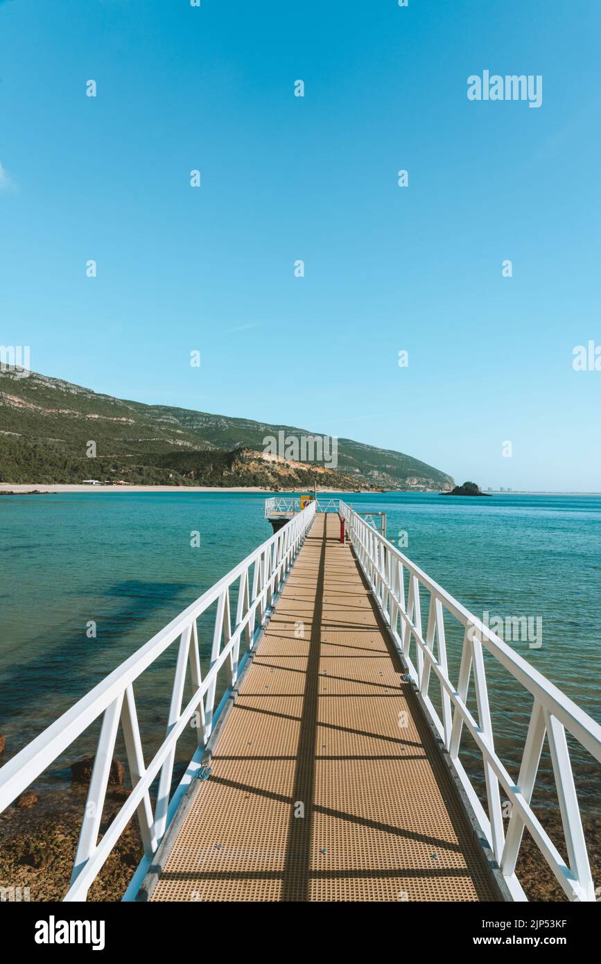 A small pier in a blue water beach in Arrabida National Park in ...