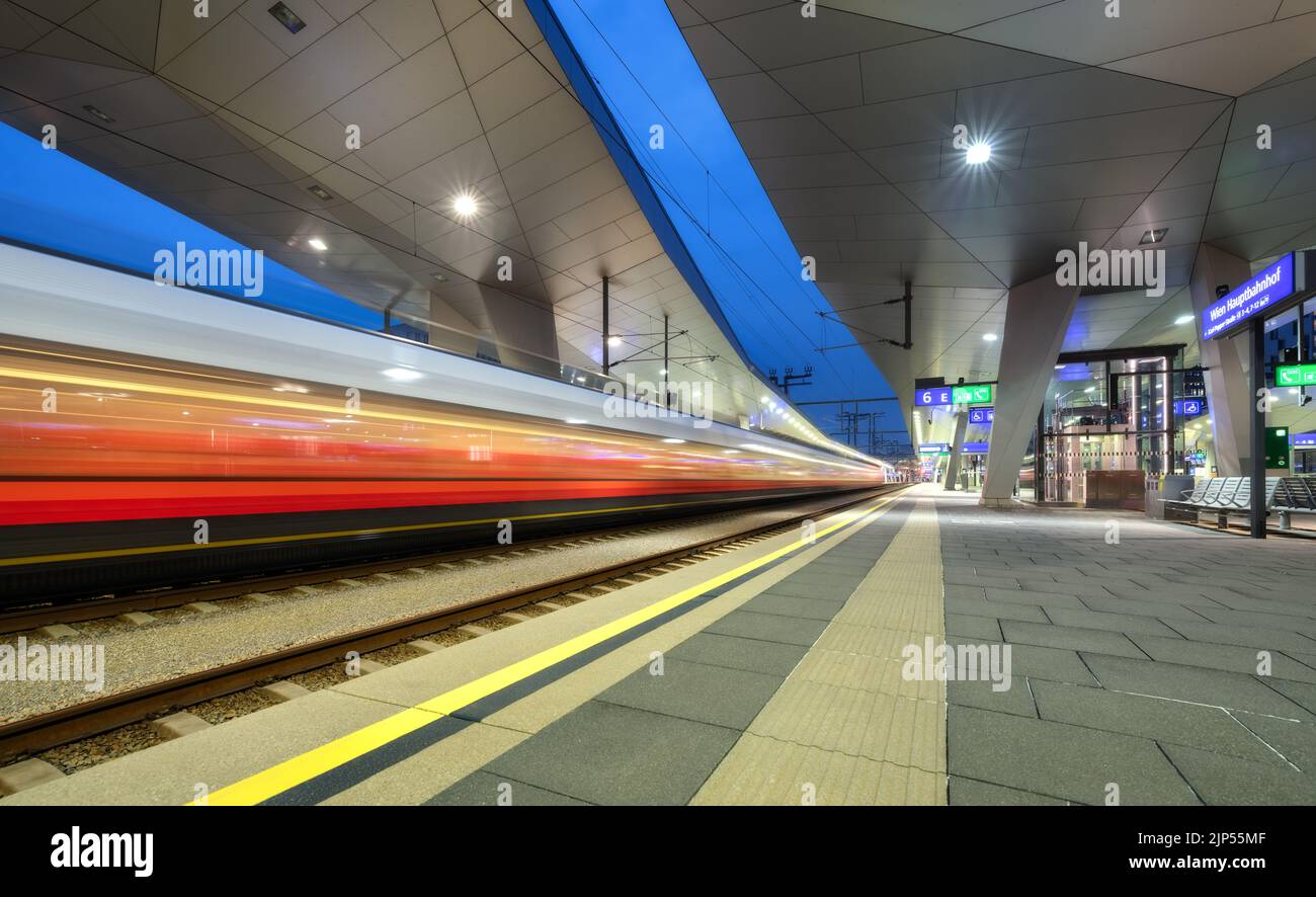 High speed train in motion on the railway station at night. Moving red ...