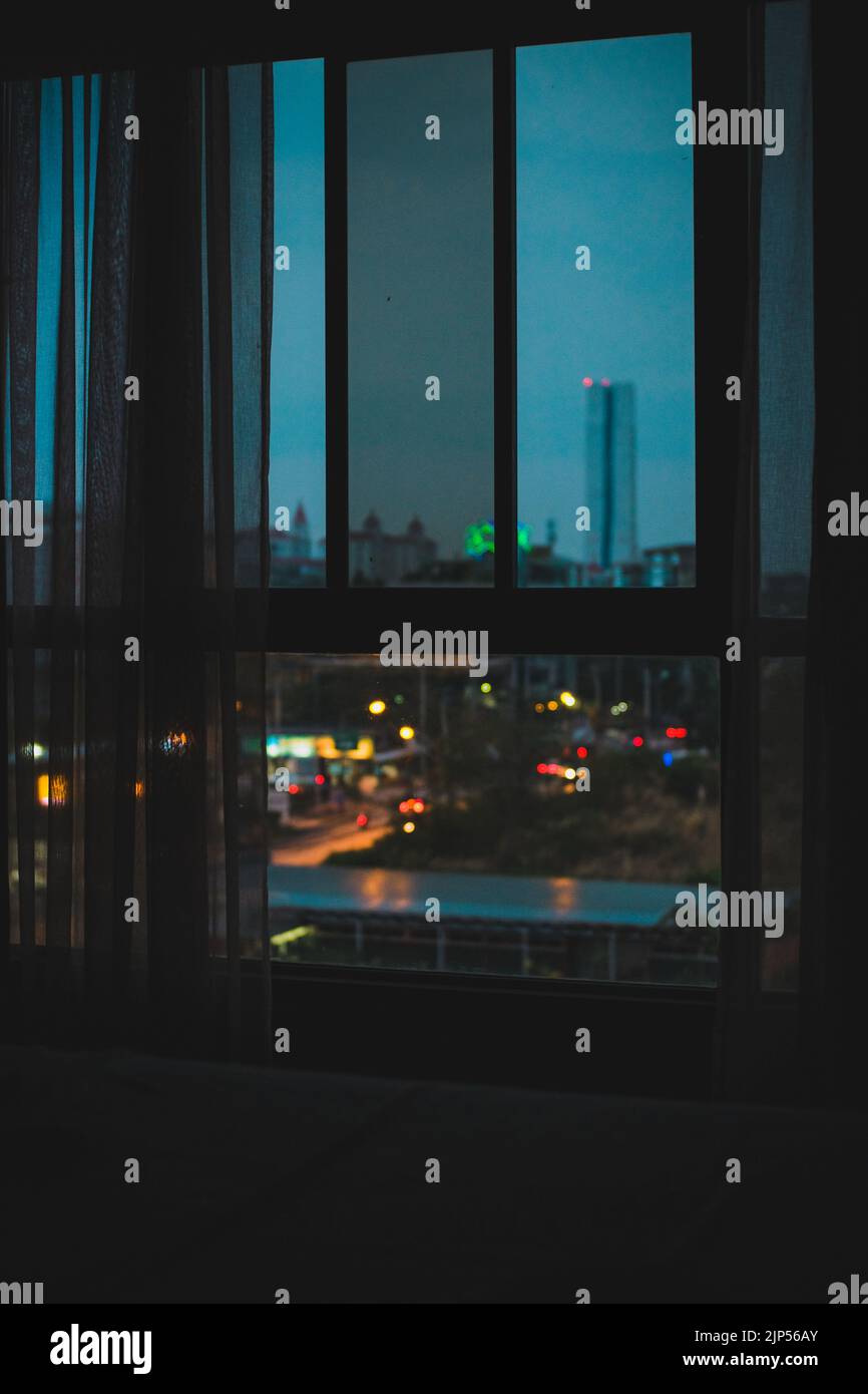 A vertical shot of night city lights from a window in a dark room Stock ...