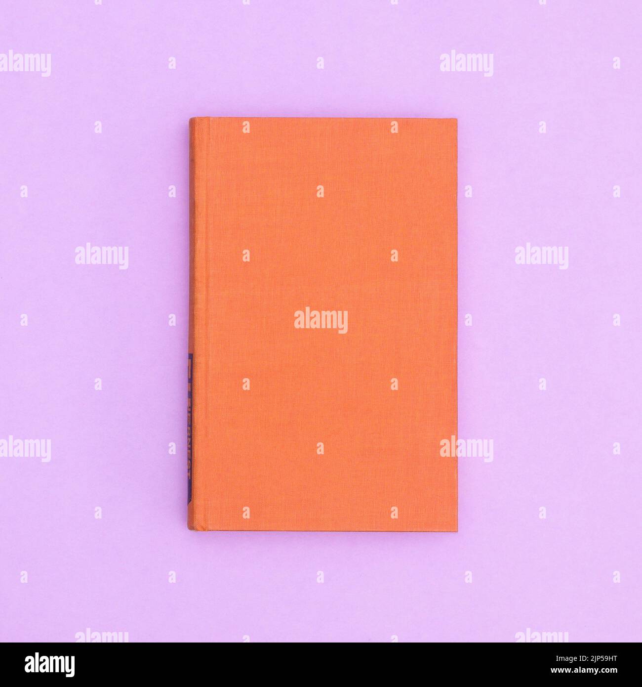 Orange hardcover vintage book on pastel purple background. Flat lay ...
