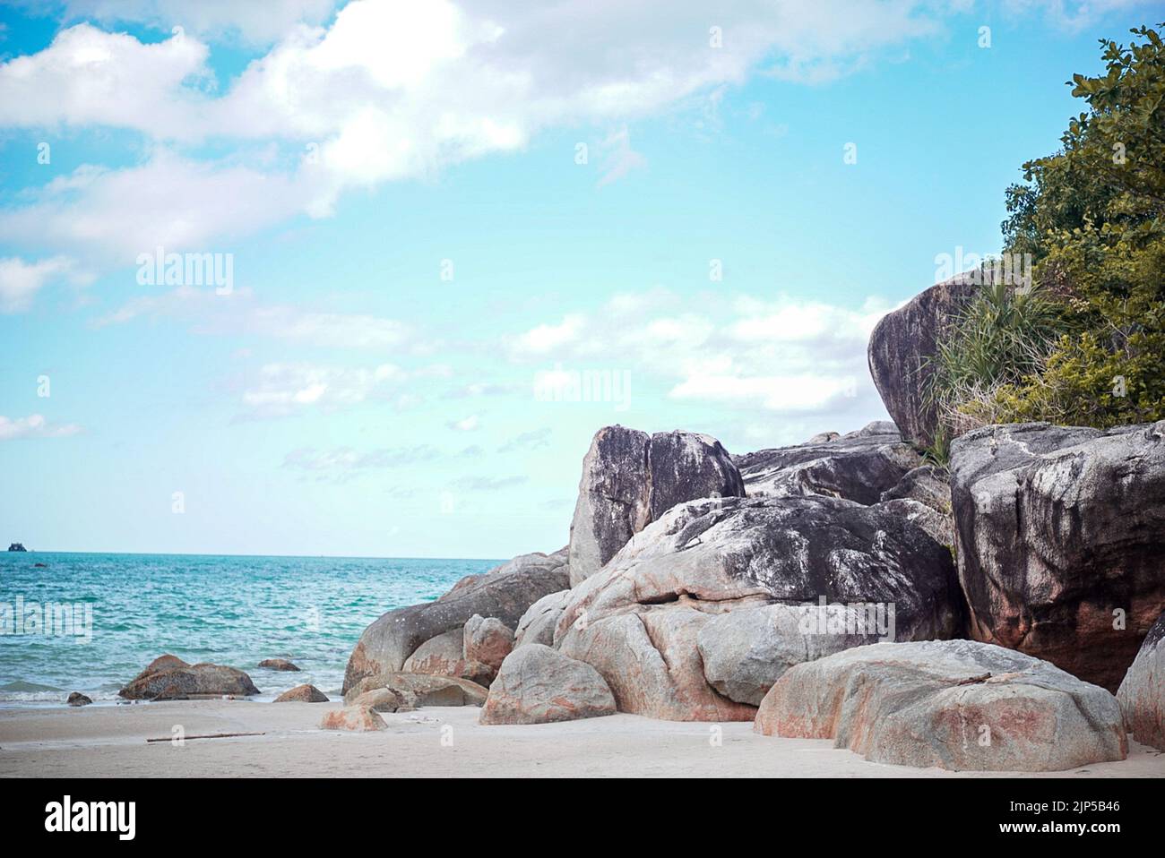 A beautiful shot of calm clear ocean water coast with big rocks on the ...