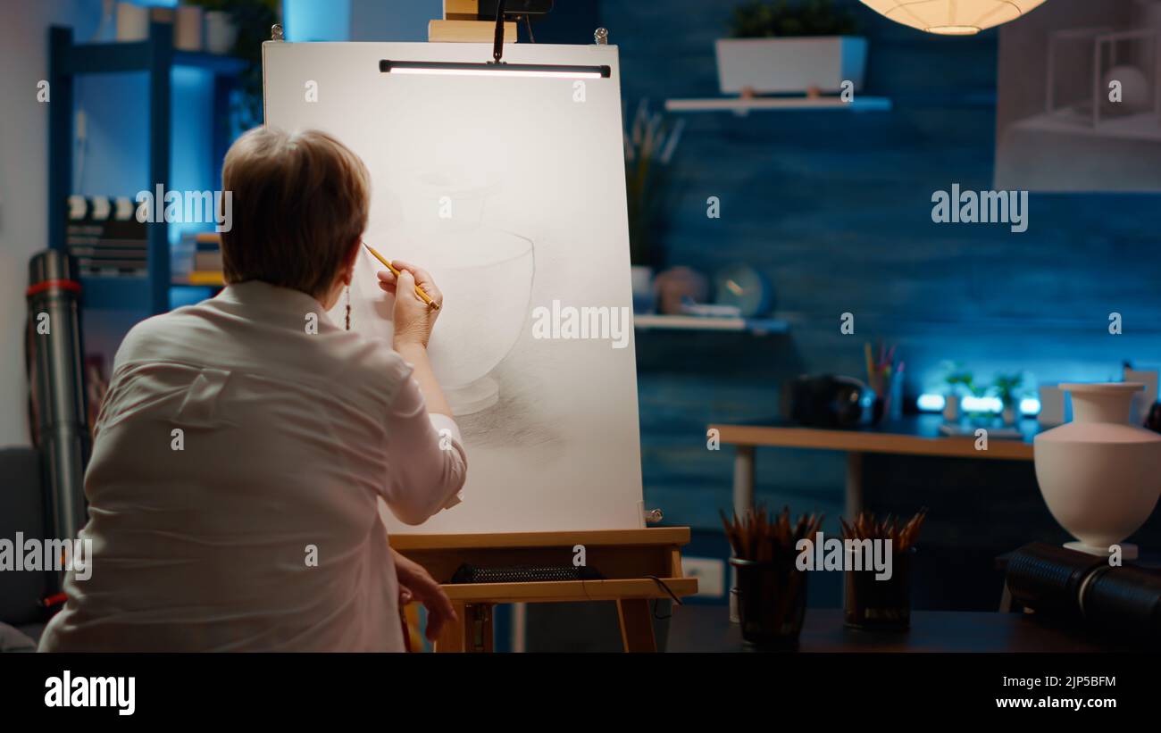 Female artist in retirement age using pencils to draw vase artwork on ...
