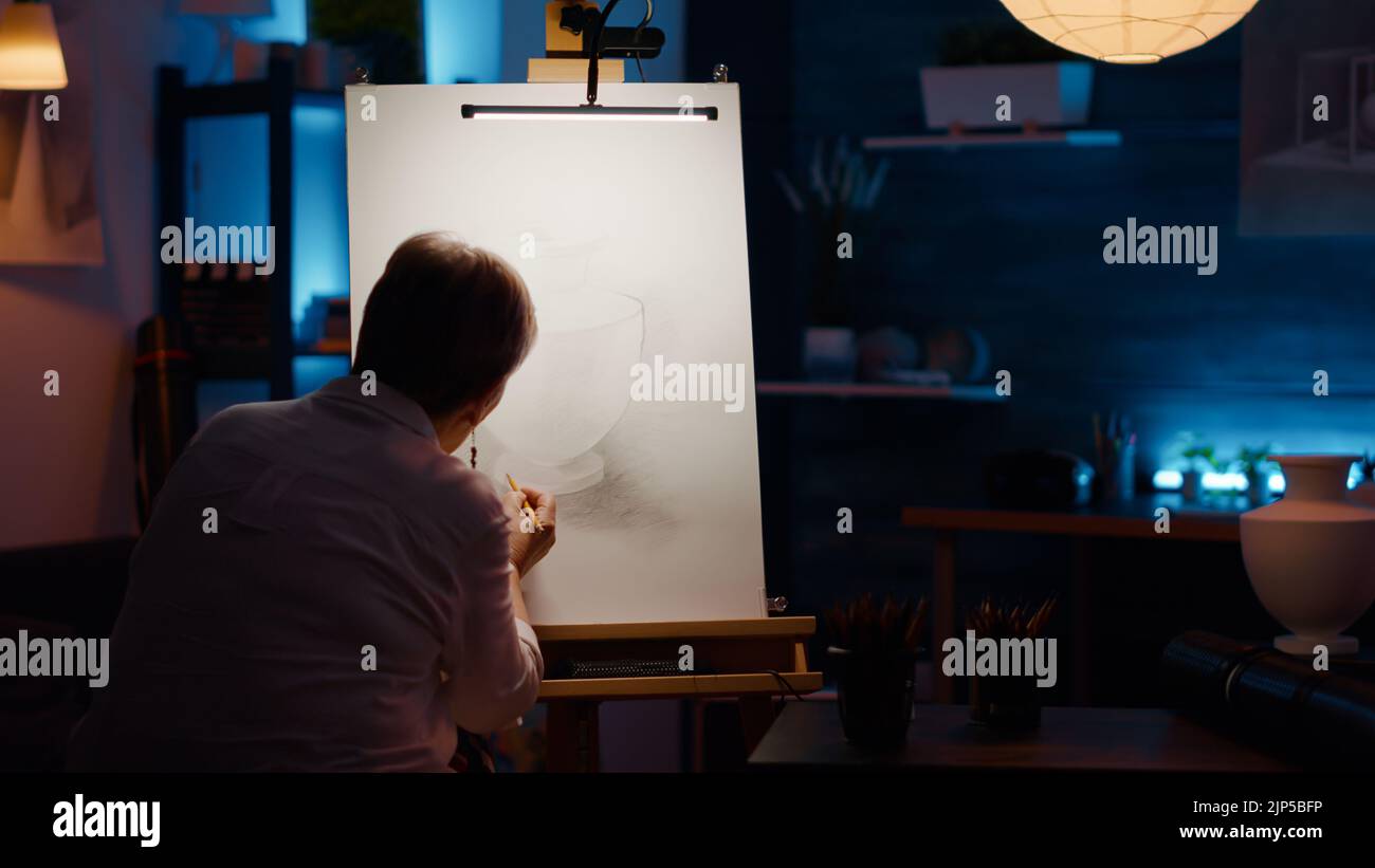 Old woman with creative skills drawing professional artwork with vase ...