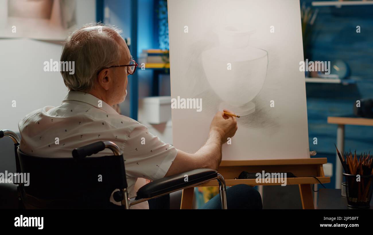 Male wheelchair user drawing vase design sketch on canvas, using ...