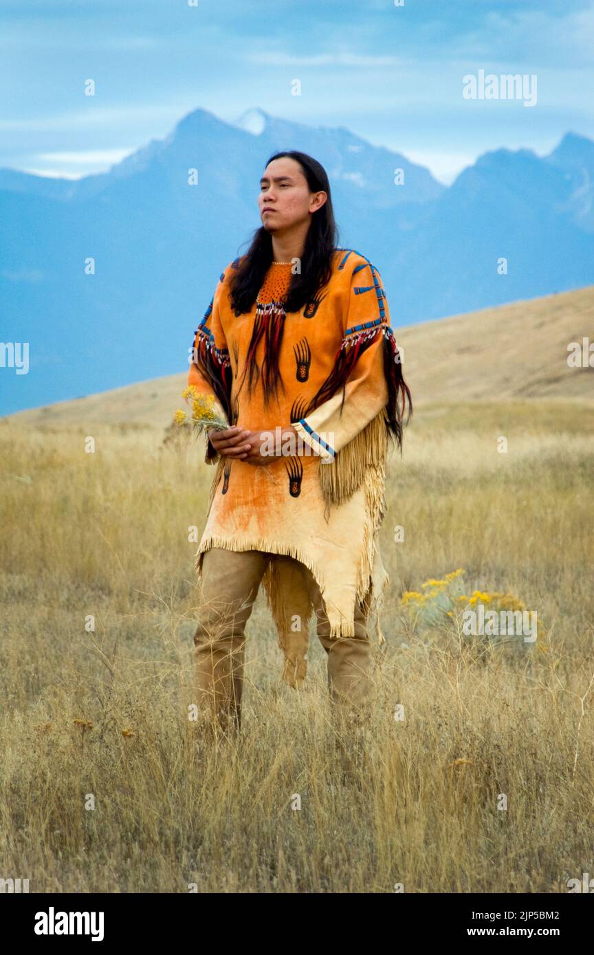 Blackfeet man dressed in traditional beaded shirt and leggings stands ...