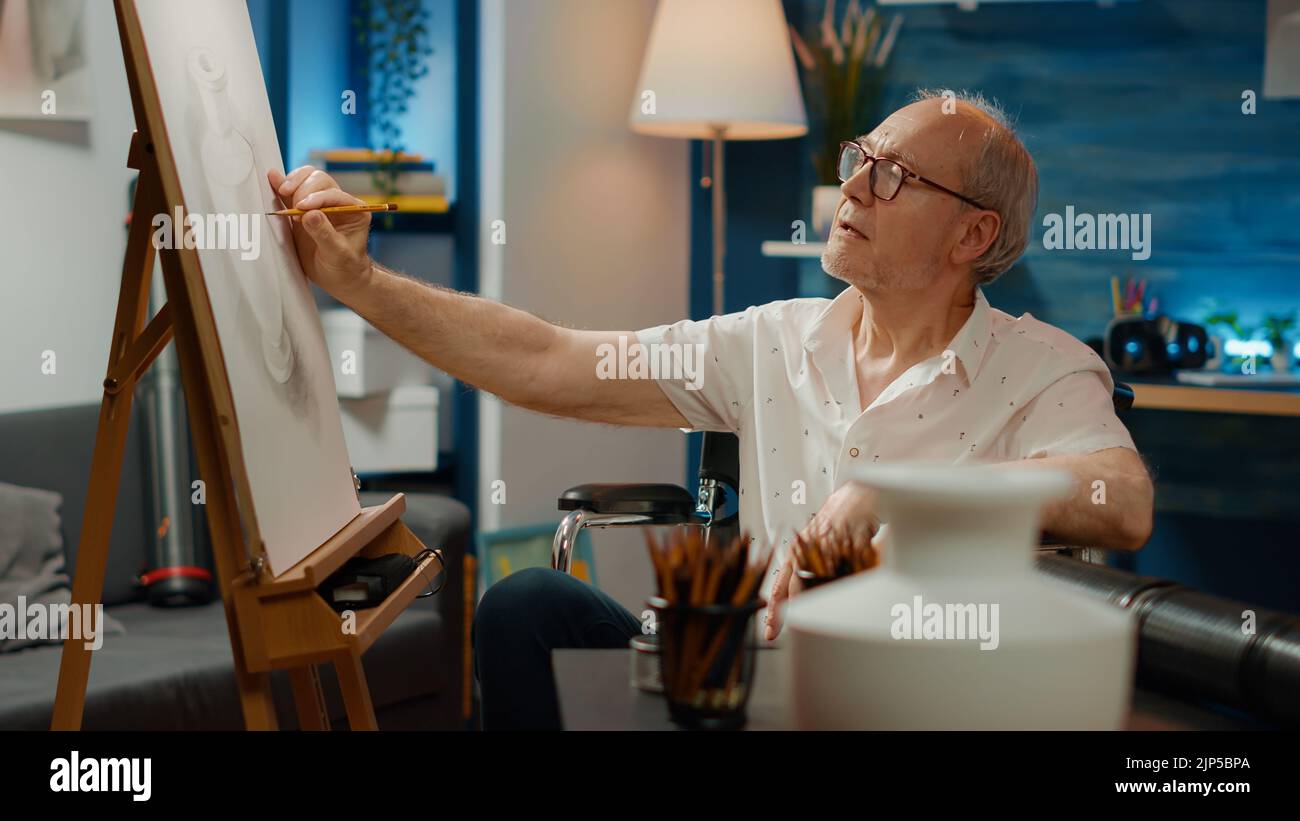 Male artist with chronic impairment drawing vase design on canvas ...