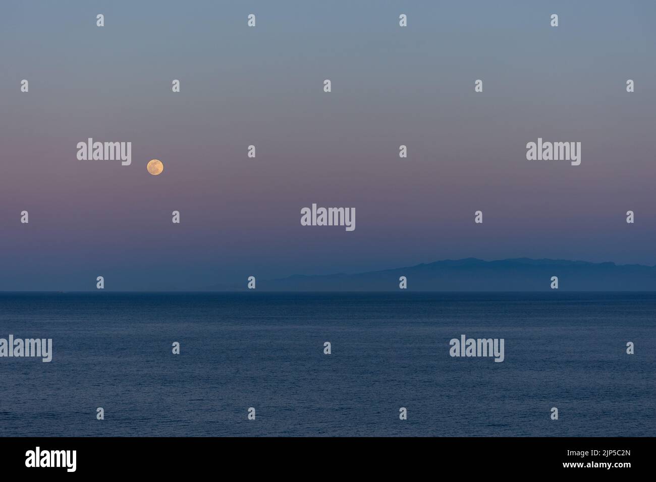 A beautiful view of a clear purple sky with a full moon over the sea ...