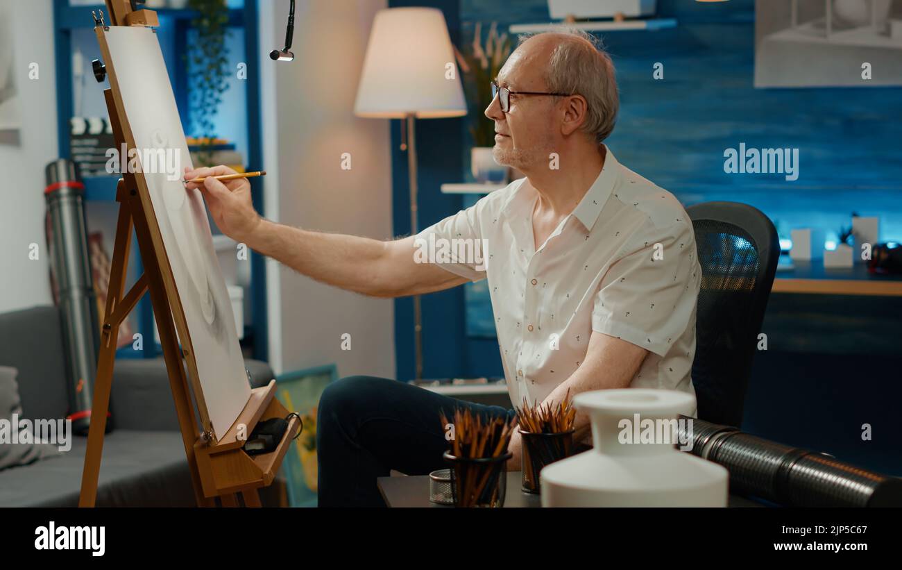Senior artist drawing professional artwork with vase model, creating ...