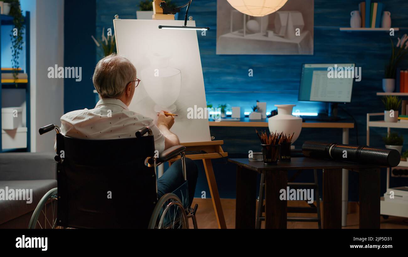 Senior adult with chronic impairment using pencils to draw vase model ...