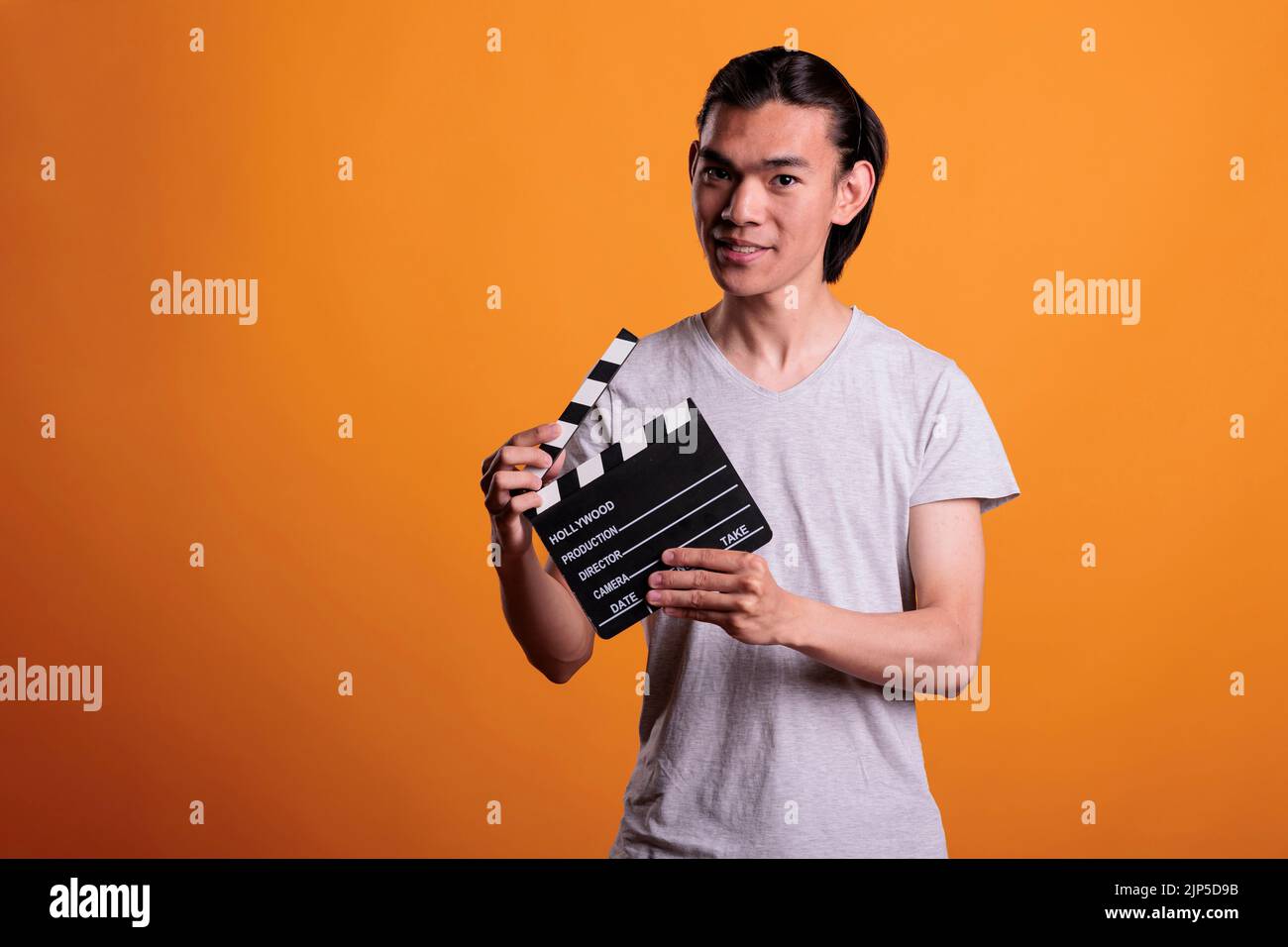 Young asian cameraman assistant slapping film making clapperboard ...