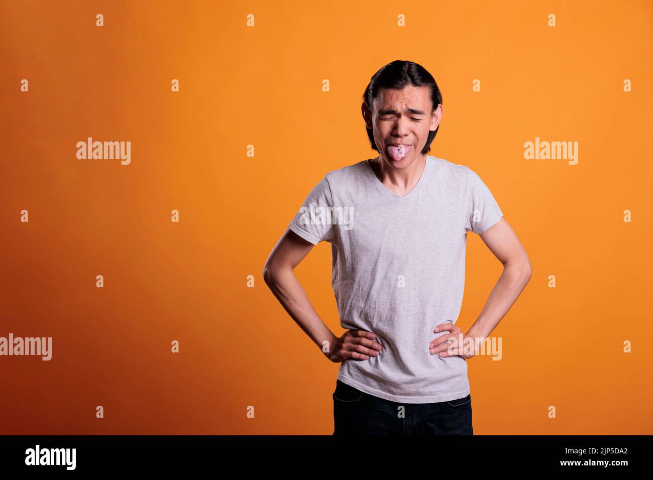 Young asian man being silly, showing tongue, making funny grimace ...