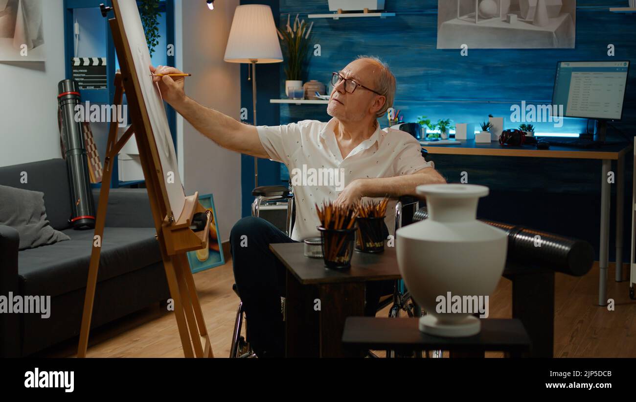 Old man with physical disability using artistic tools to draw vase ...
