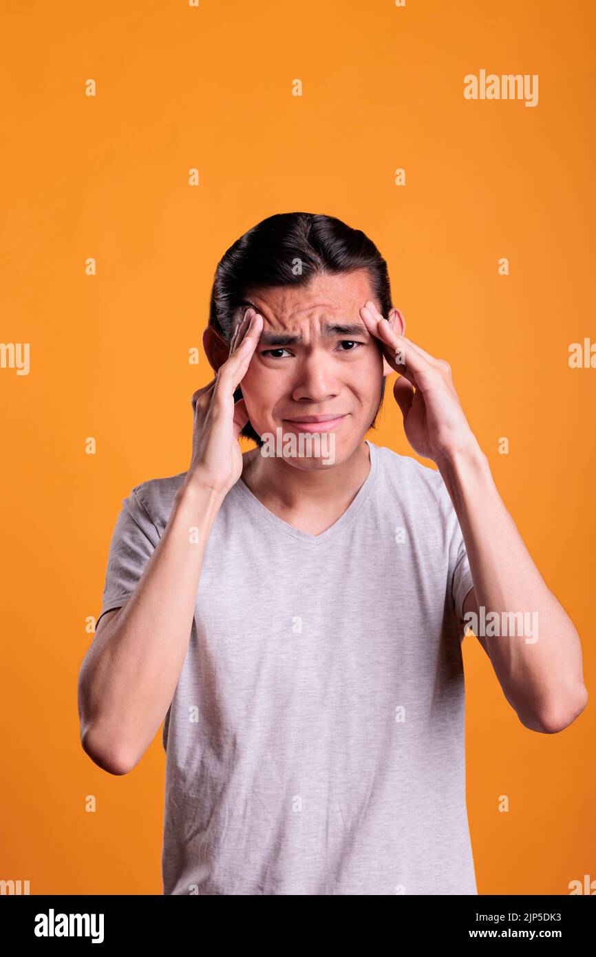 Asian man suffering from headache, touching temples with fingers ...