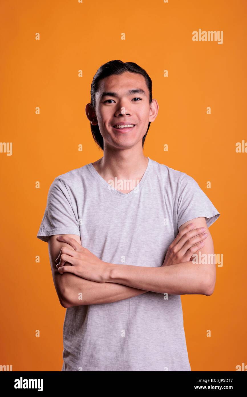 Young smiling happy asian man standing with arms crossed, looking at ...