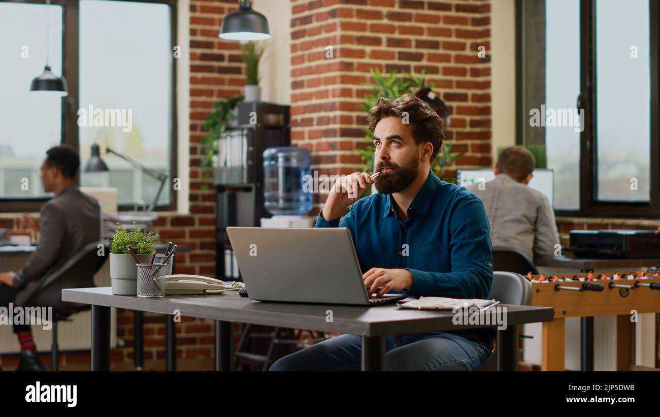 Thoughtful businessman brainstorming ideas to create report on laptop ...