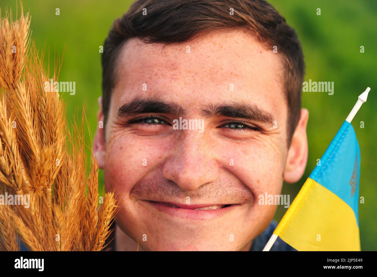 Defocus young ukrainian man portrait. Bouquet of ripe golden spikelets ...