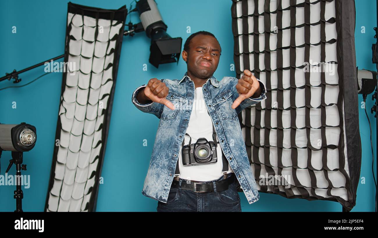 Young man showing thumbs down dislike gesture in studio with ...