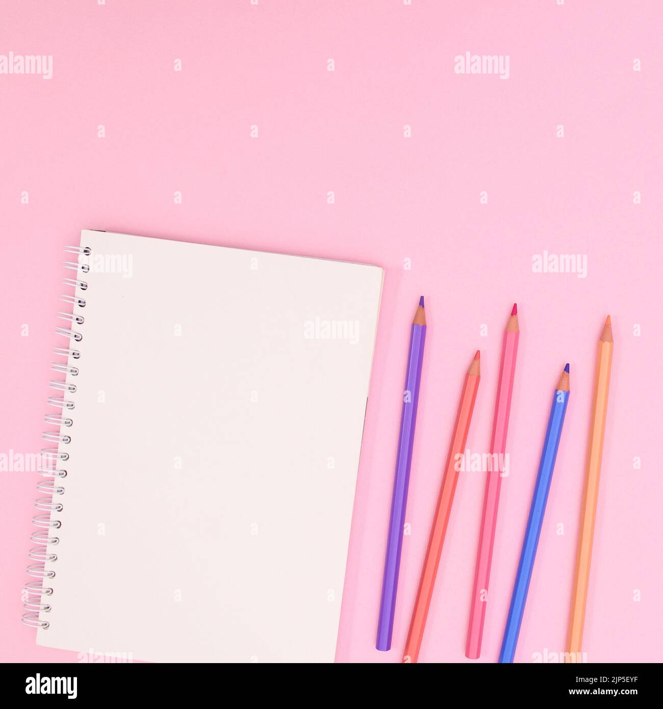 Pastel wooden pencils with open notebook copy space on pastel pink ...