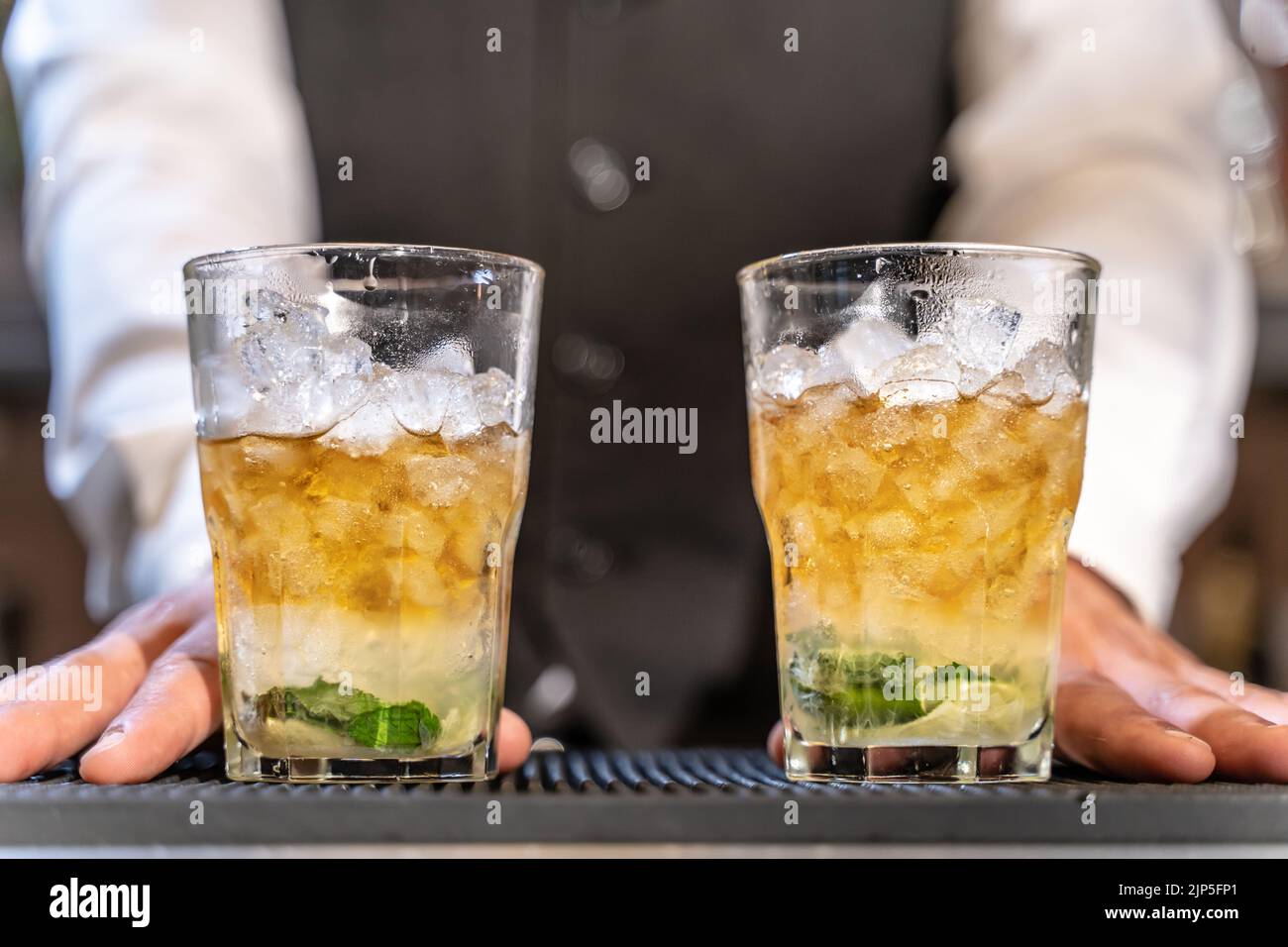 Barman serves Mojito in night club adding ingredients and creating ...