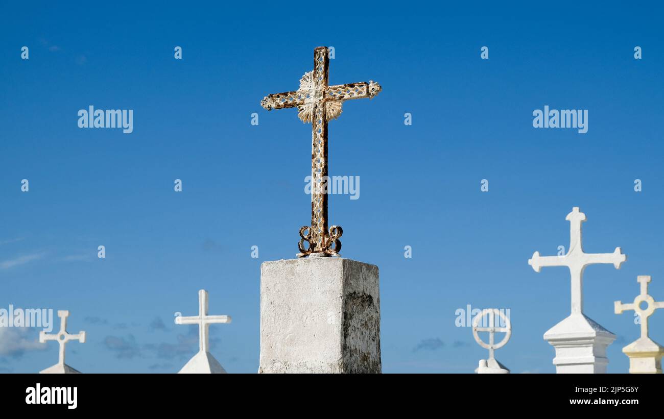 A group of metal grave crosses on stone pedestals with blue sky in the ...