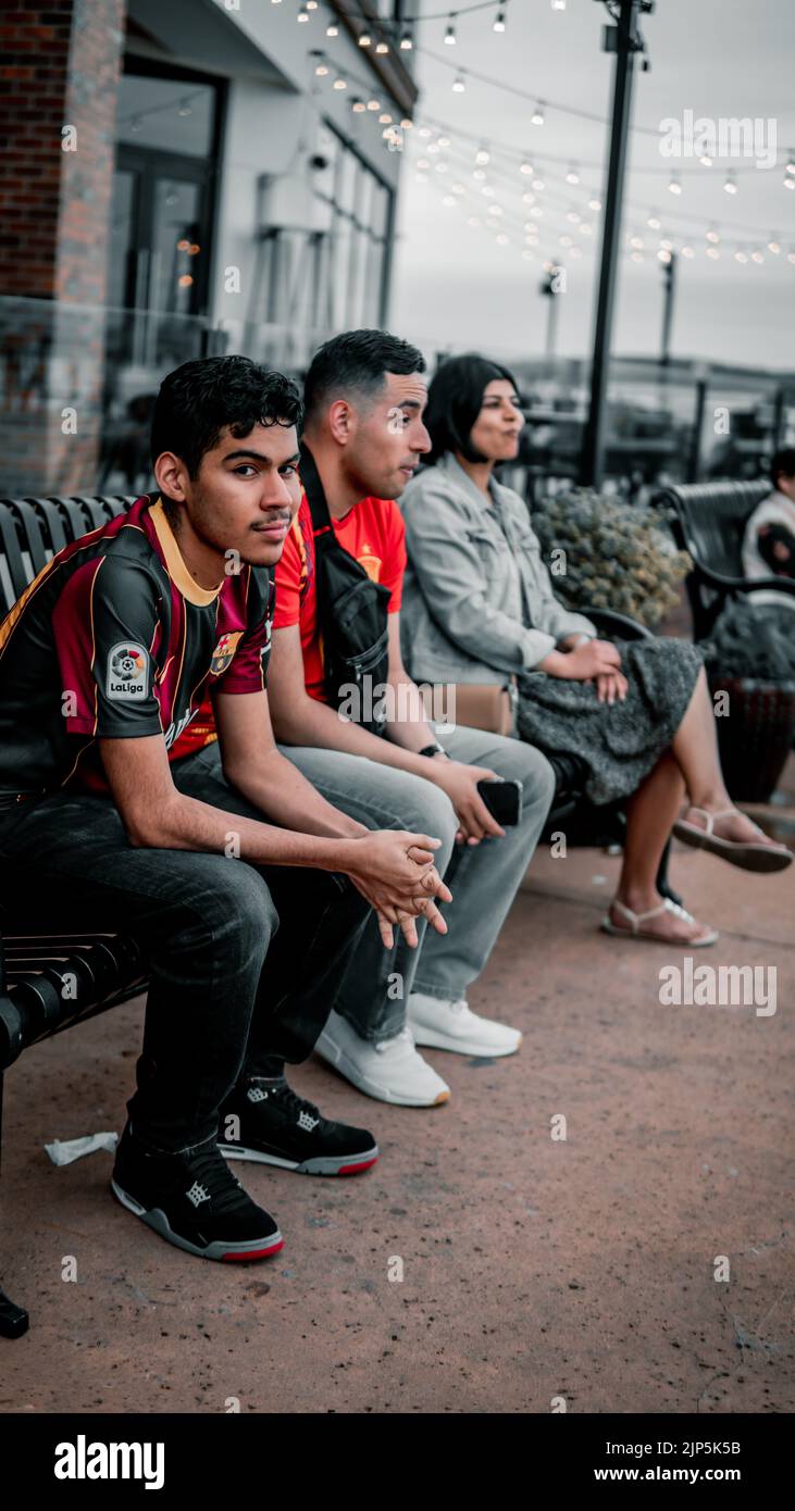 A group of people sitting on bench in the city center on a sunny day ...